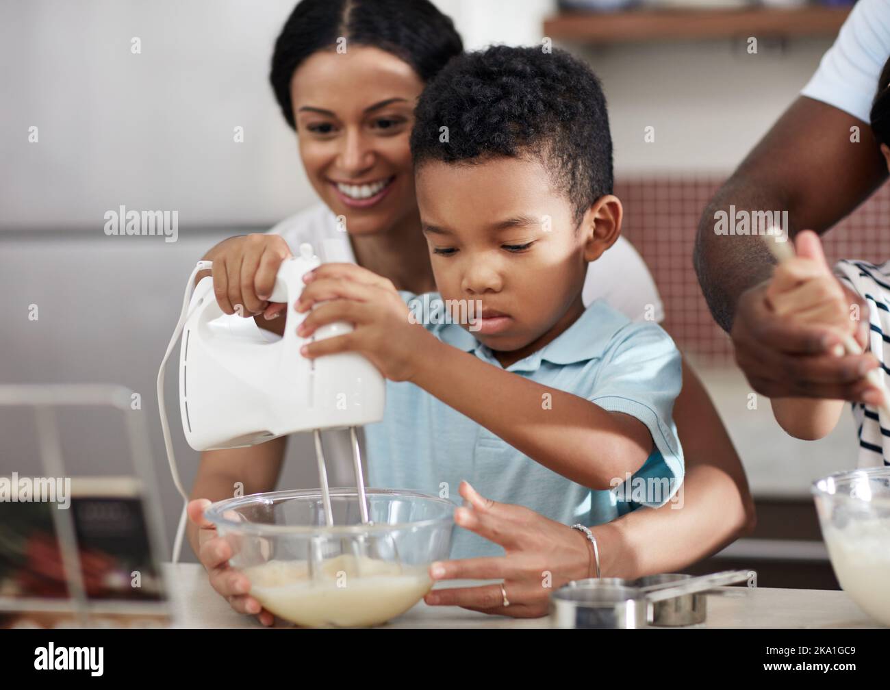You doing a great job. a young mother helping her son bake in the ...