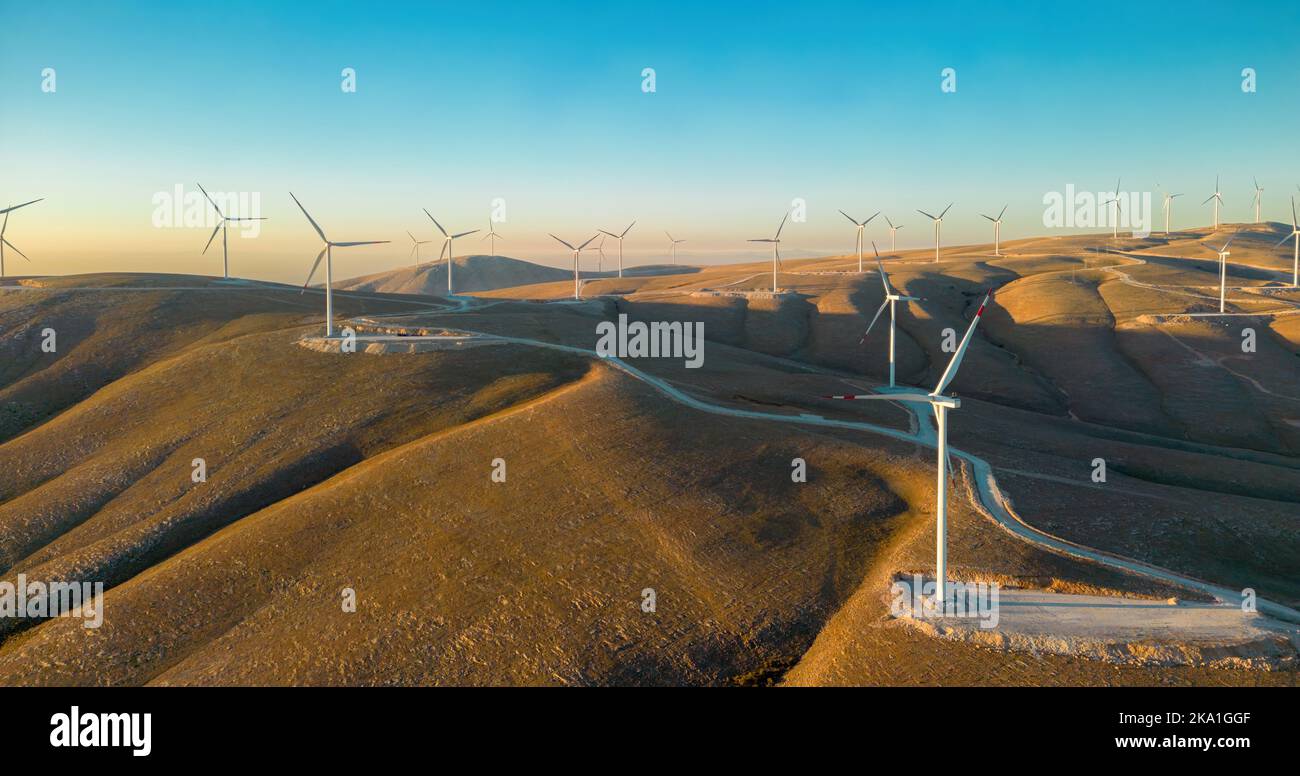 Aerial view of multiple wind turbines standing on a hill and generating ...