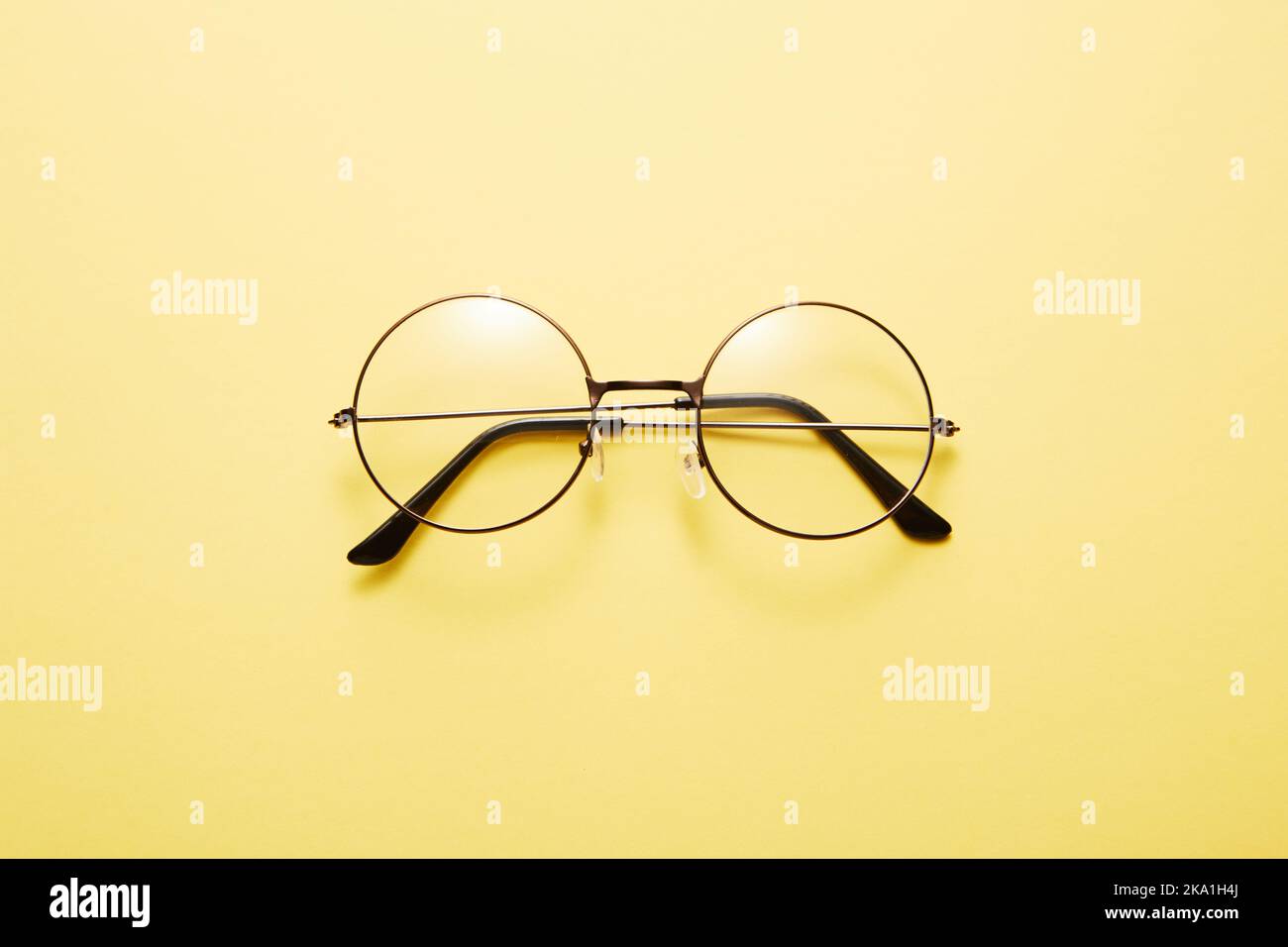Glasses in round thin metal frame isolated on yellow surface Stock ...