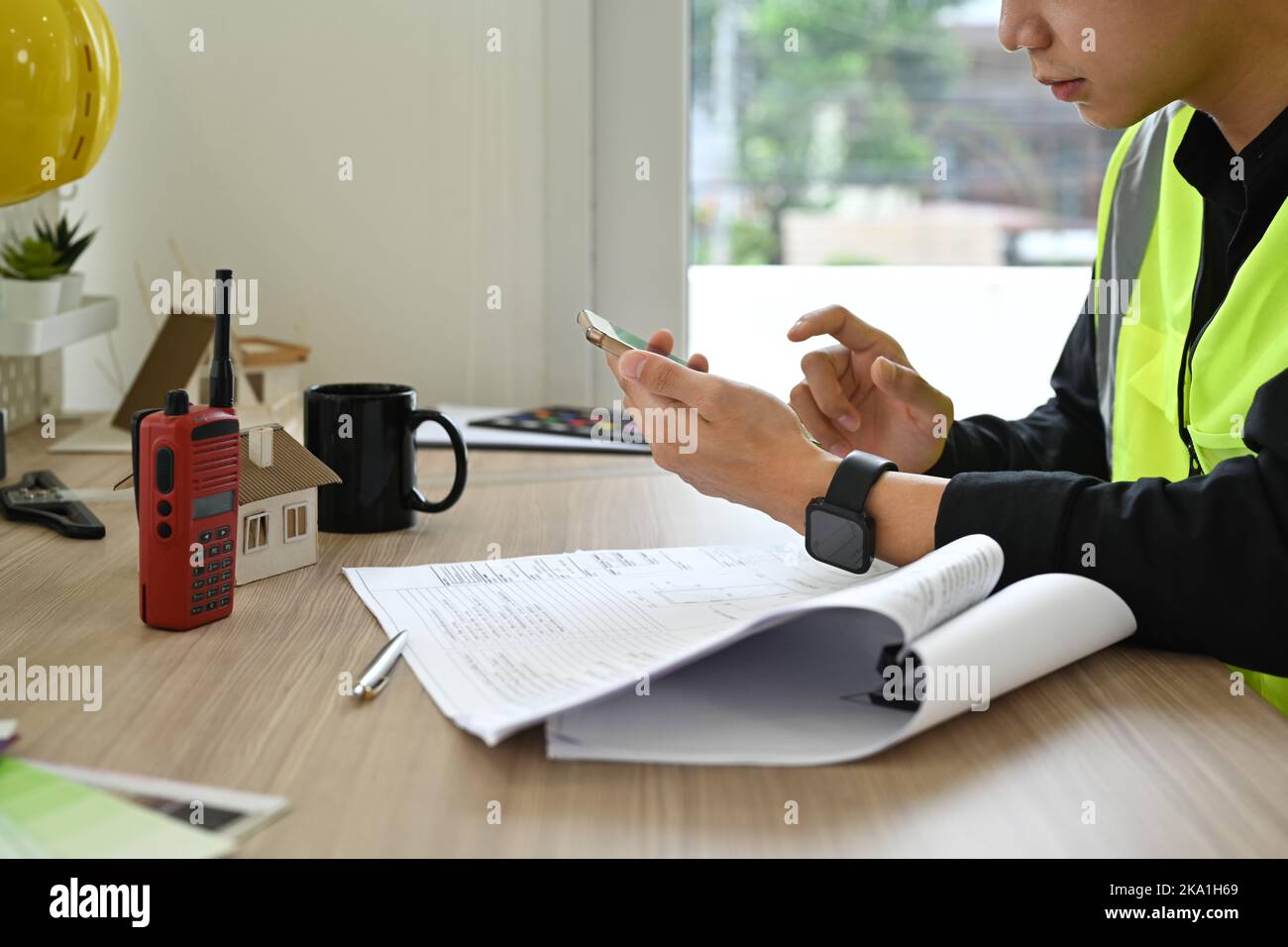 Civil engineer wearing vest working with blueprints and using smart ...