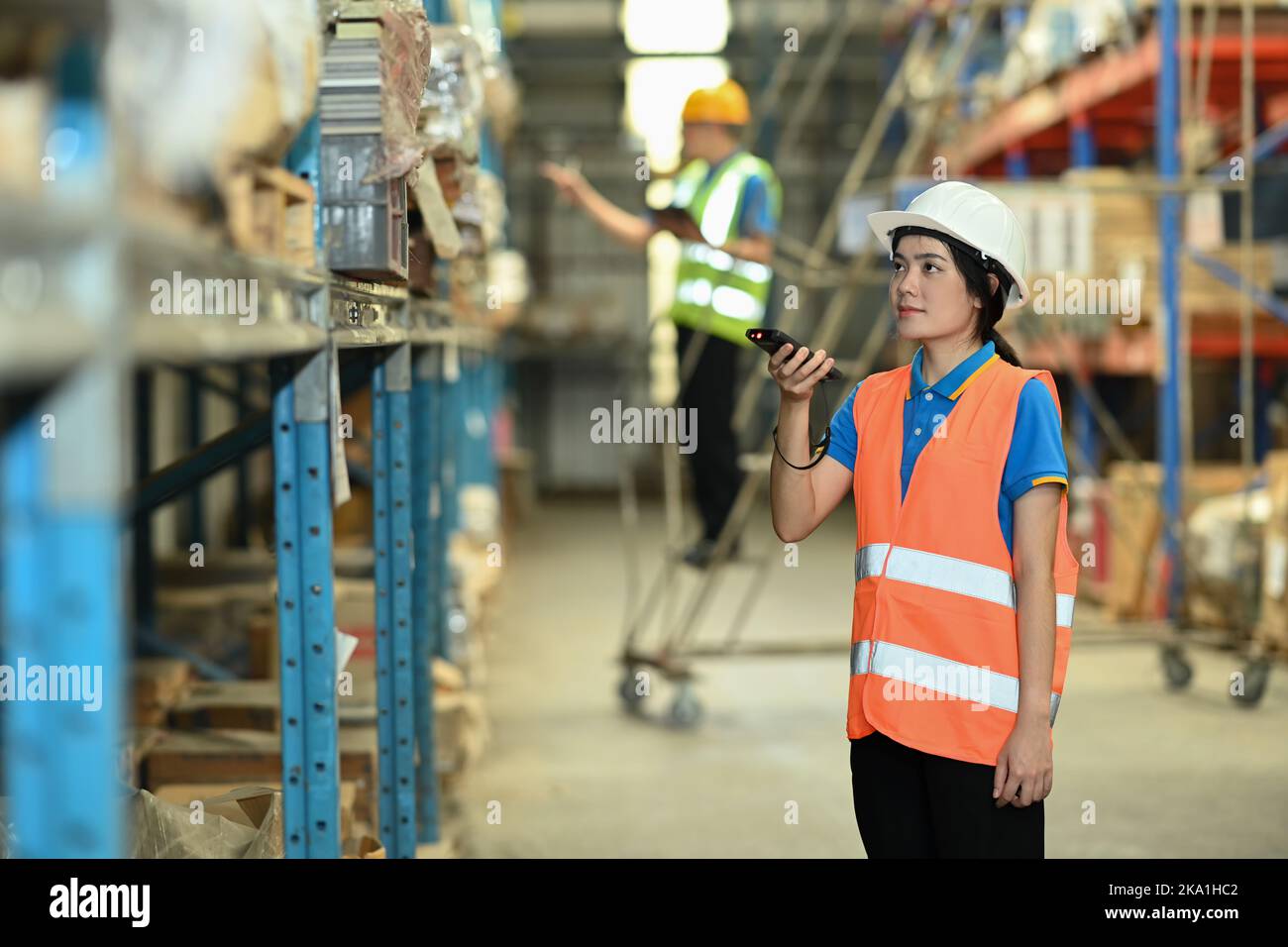 Female workers wearing hardhats and vests checking inventory boxes on ...