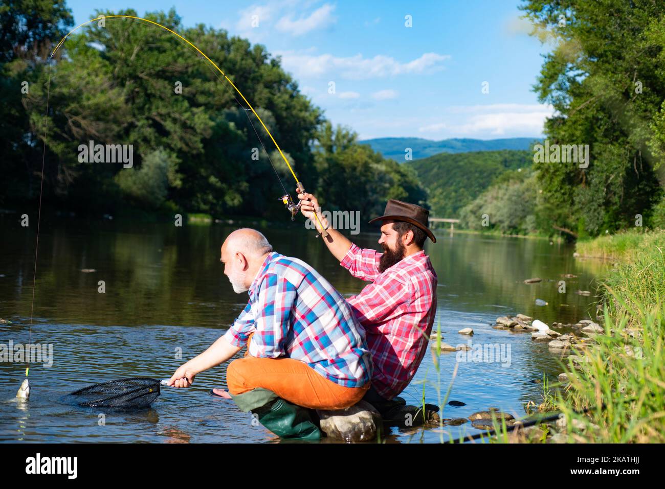 Two men friends fisherman fishing on river. Old father and son with rod ...