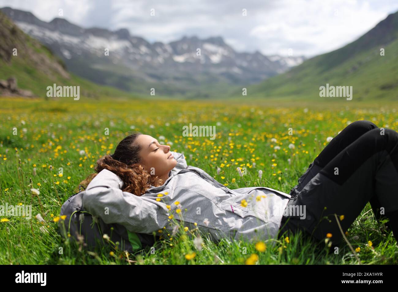 Hiker resting lying on the grass in a valley of a high mountain Stock ...