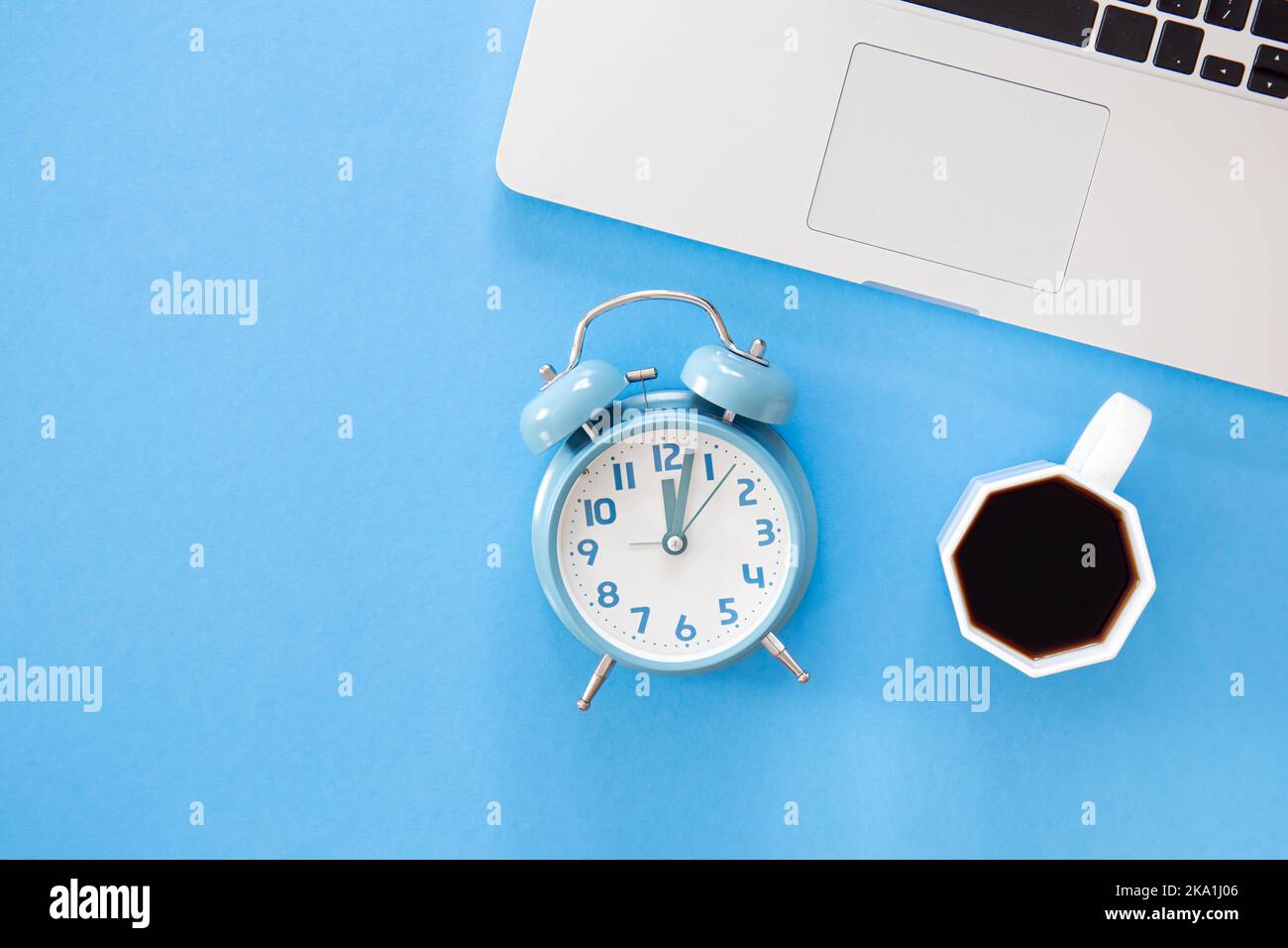 Alarm clock, laptop and coffee cup on blue background, flat lay Stock ...