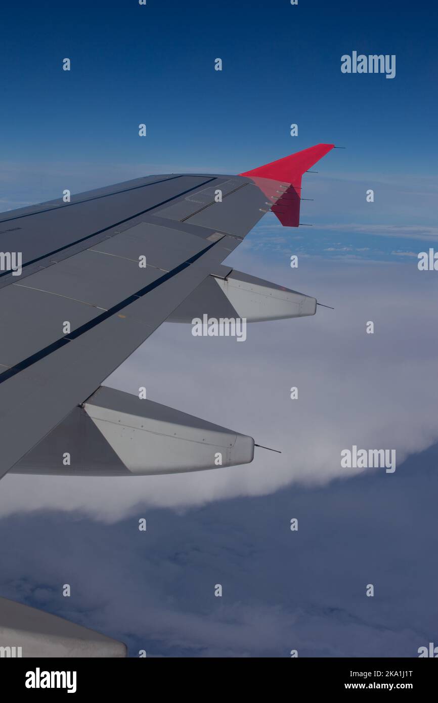 The wing of a medium-haul aircraft above the clouds and with the blue ...