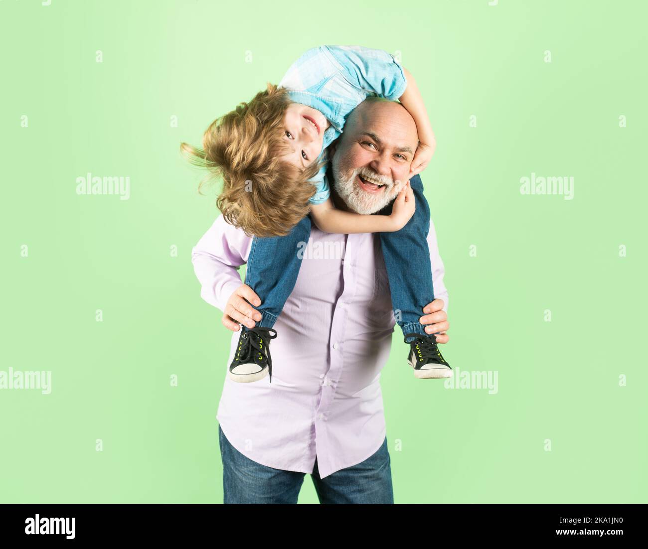 Old grandfather and young child grandson piggyback ride with funny face ...