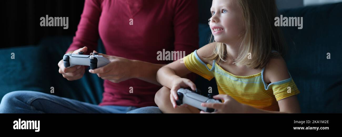 Mom and daughter hold game joysticks and play online games Stock Photo ...