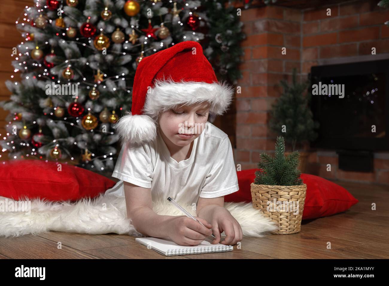 Happy Christmas kids. Boy child in Santa Claus hat writes a letter to ...