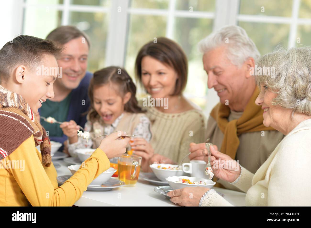Happy family of different generations eating together Stock Photo - Alamy
