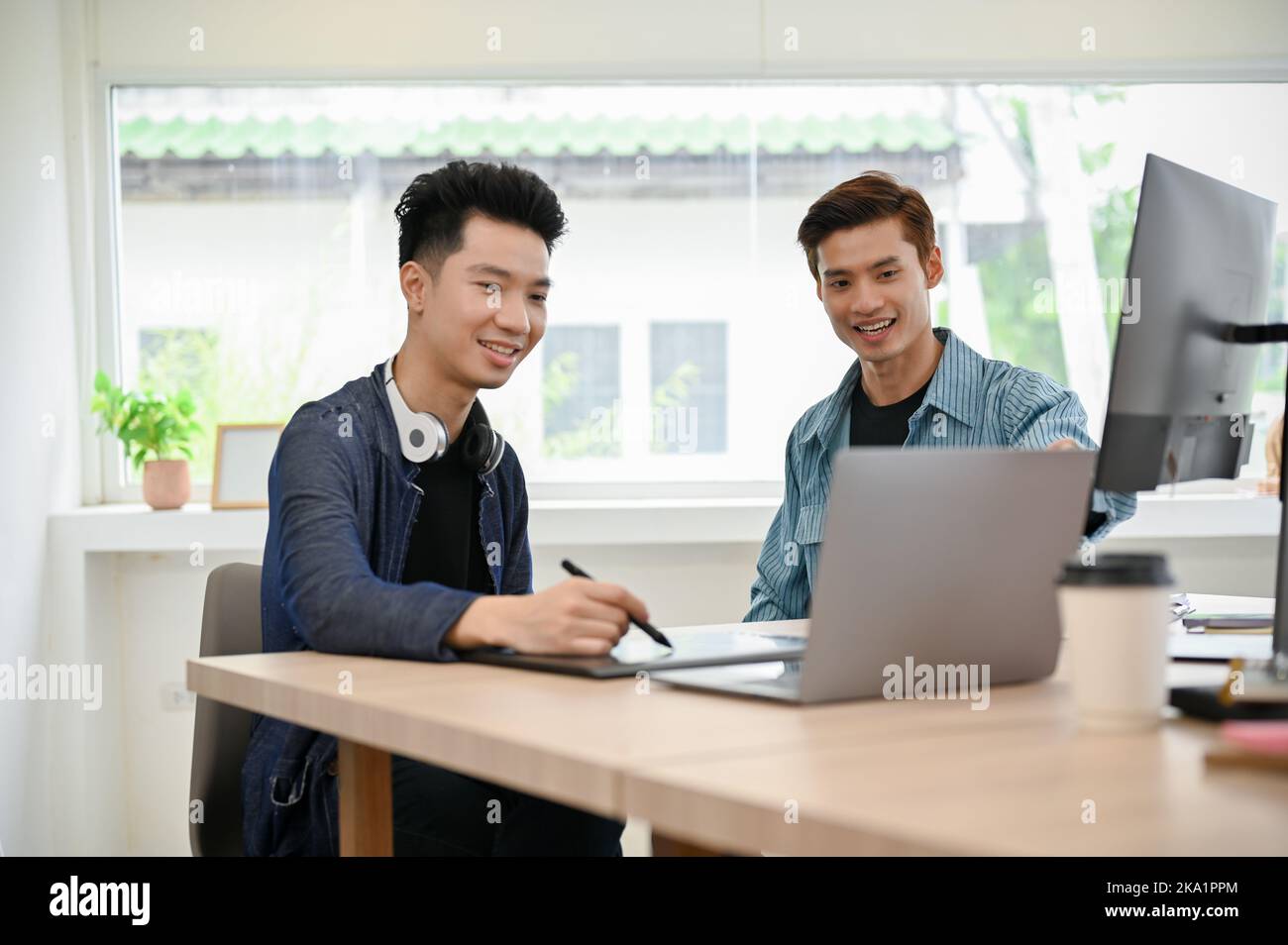 Two Professional Young Asian Male Programmers Or Photo Editors Working