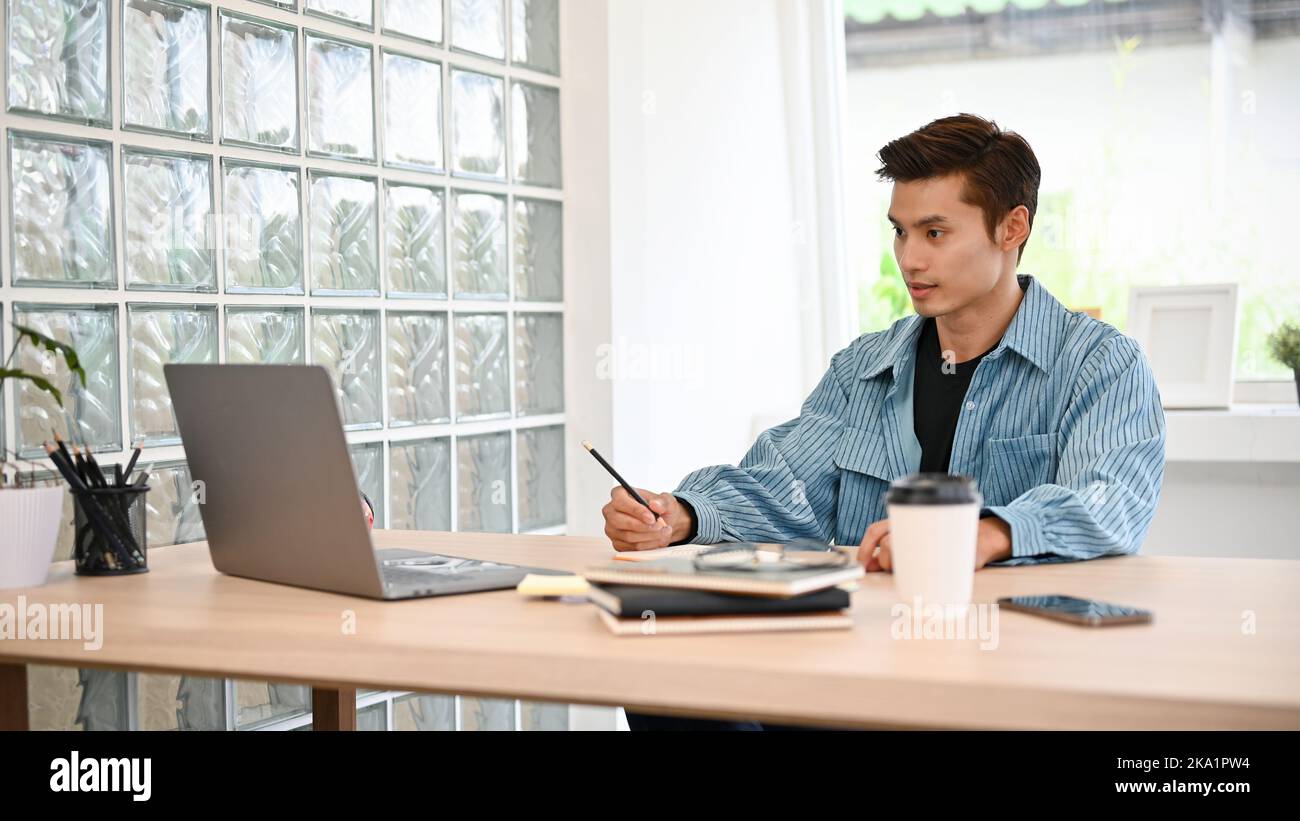 Handsome and smart millennial Asian male freelancer remote working in ...