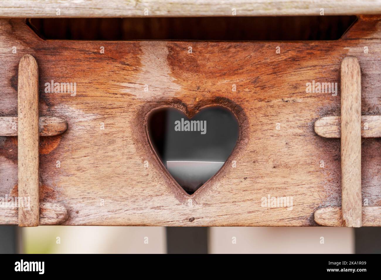 Wooden mailbox with a carved slot in a heart shape with a letter on the ...