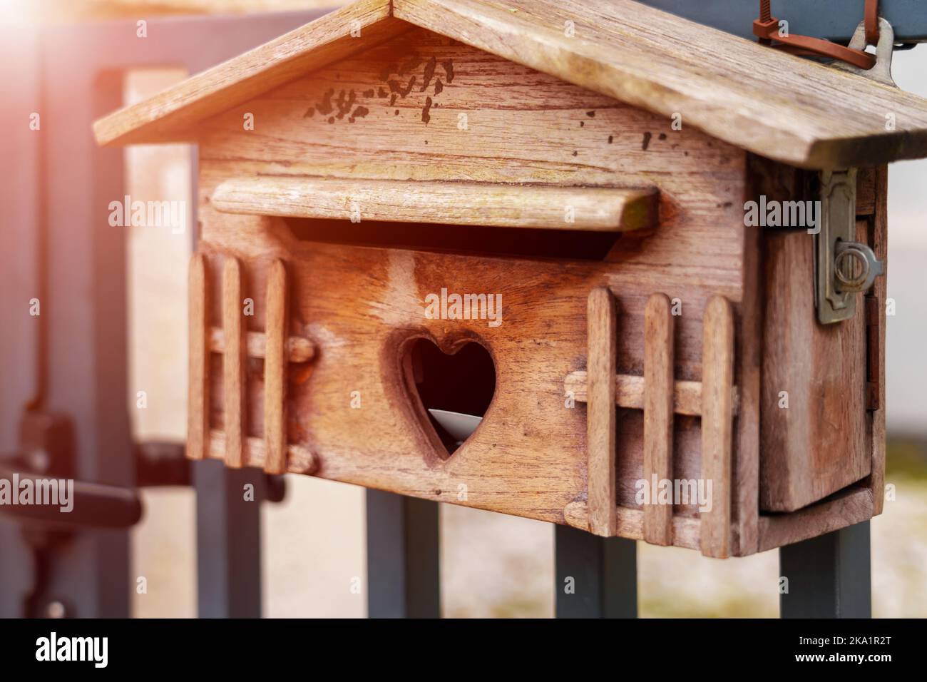 Wooden mailbox with a carved slot in a heart shape with a letter on the ...