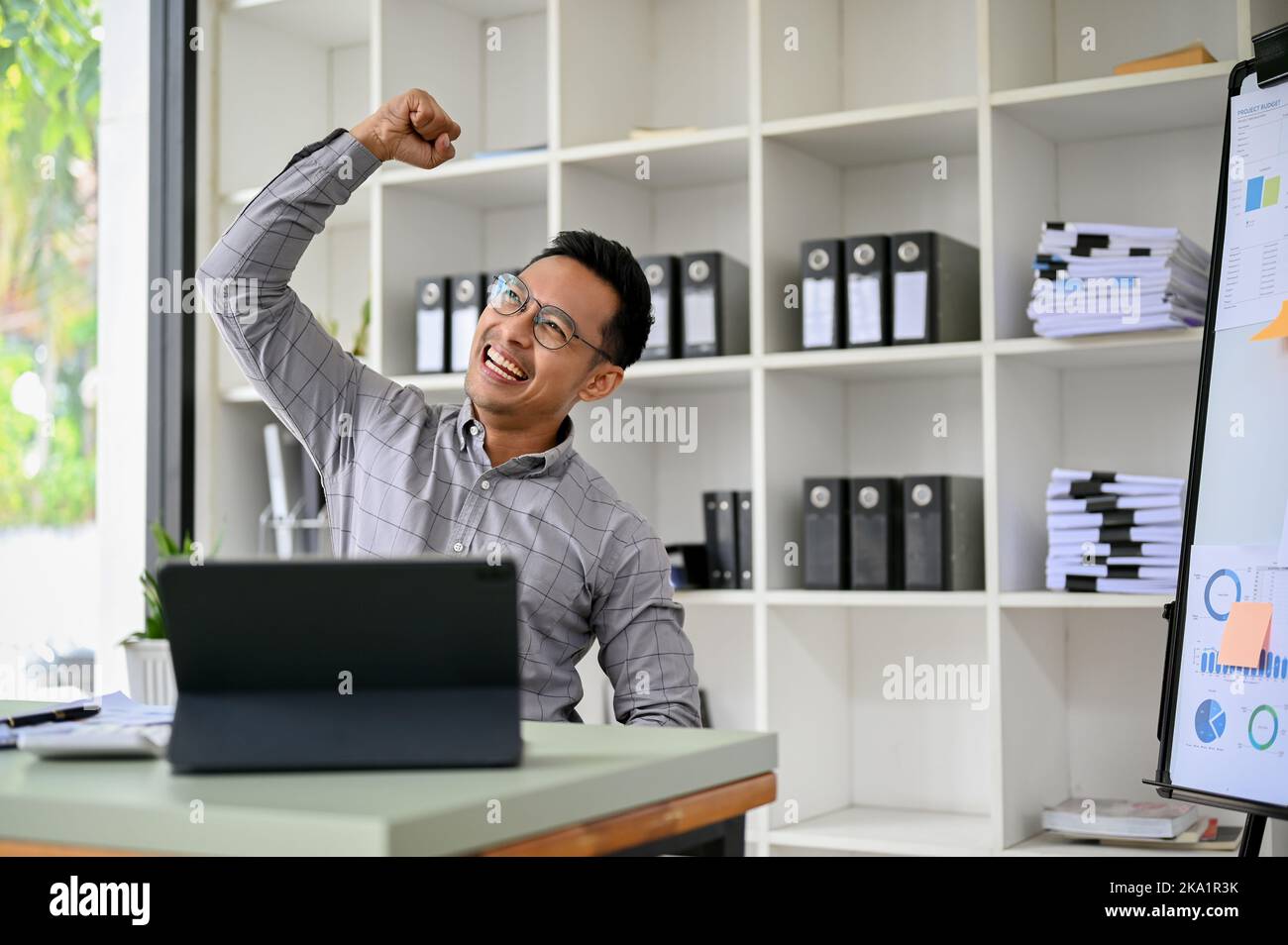 Overjoyed adult Asian businessman or male boss at his desk, showing ...