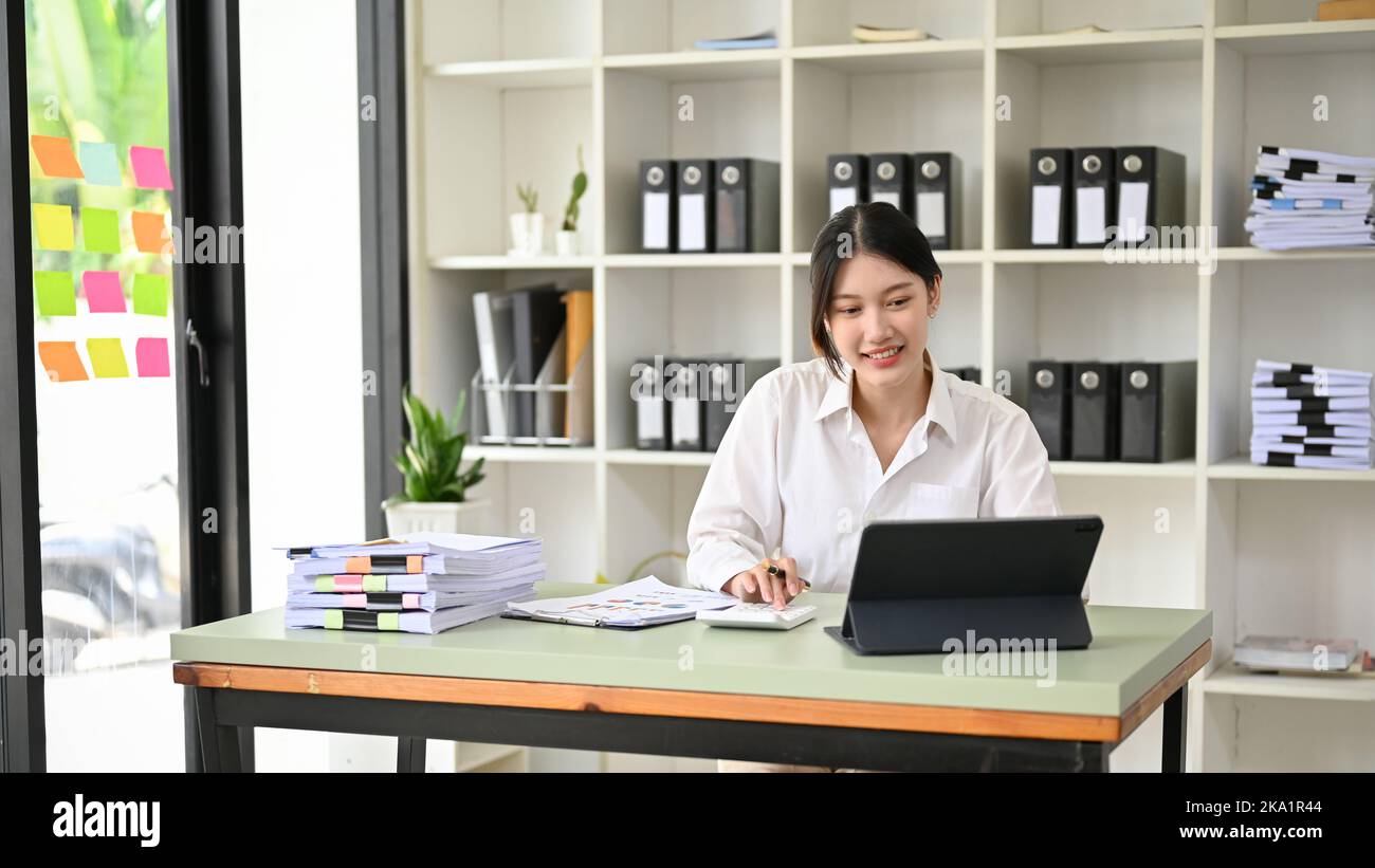 Beautiful young Asian female accountant or financial worker is working ...