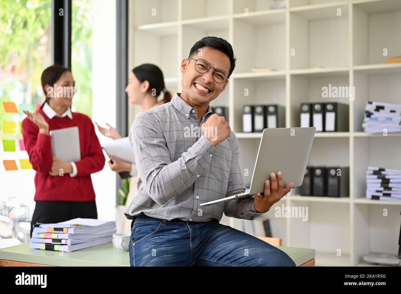 Happy and professional millennial Asian businessman holding a laptop ...
