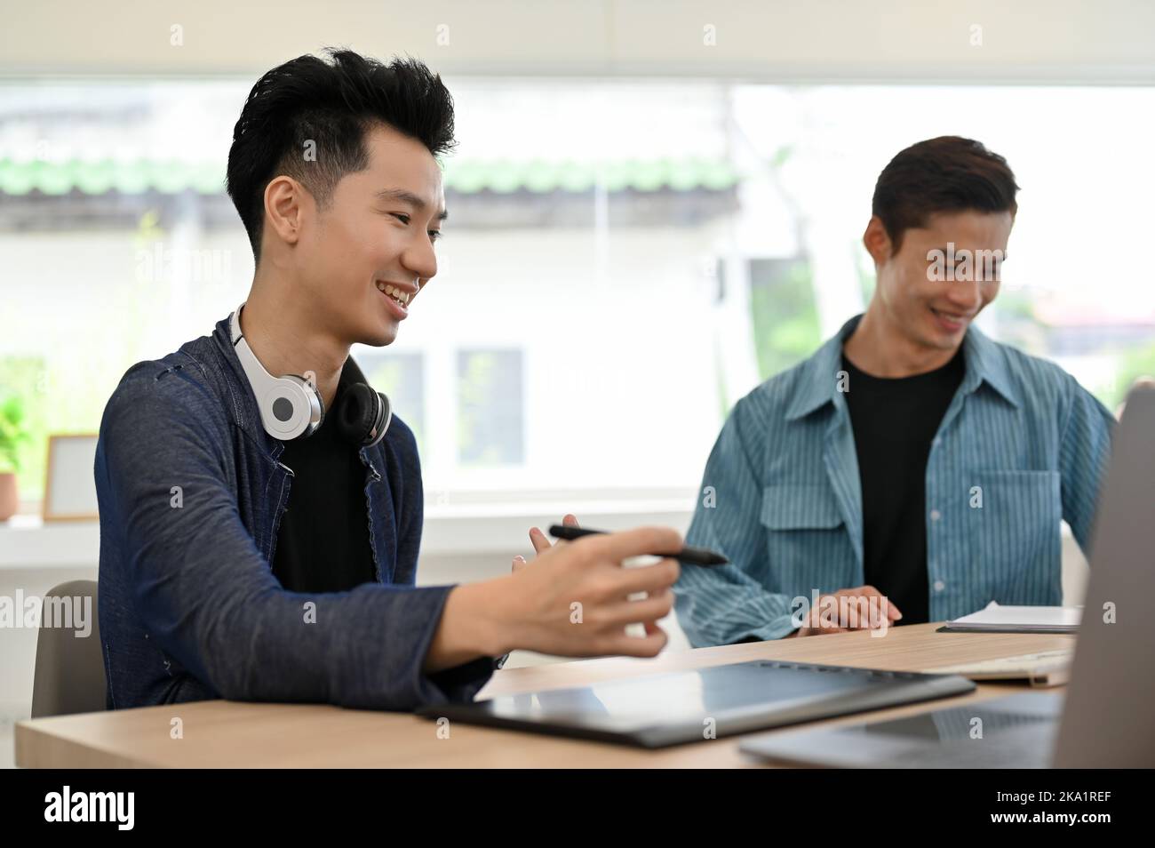 Two smart millennial Asian male web developers discussing and working together in the meeting ...