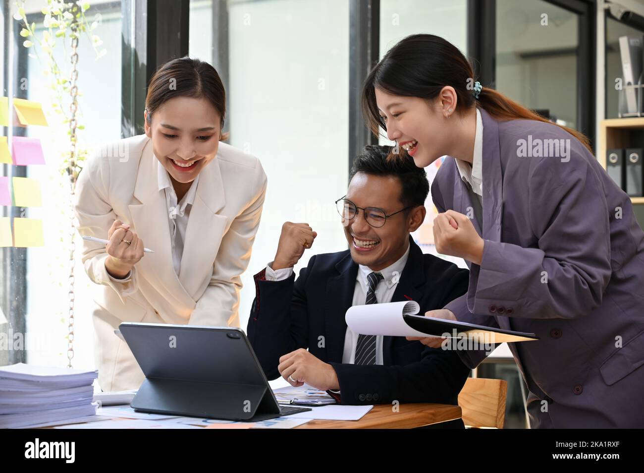 Cheerful and overjoyed millennial Asian businesspeople celebrating ...
