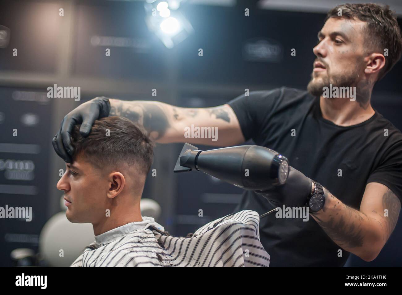 Modern urban hairdresser cut and adjusts the hairstyle in professional ...