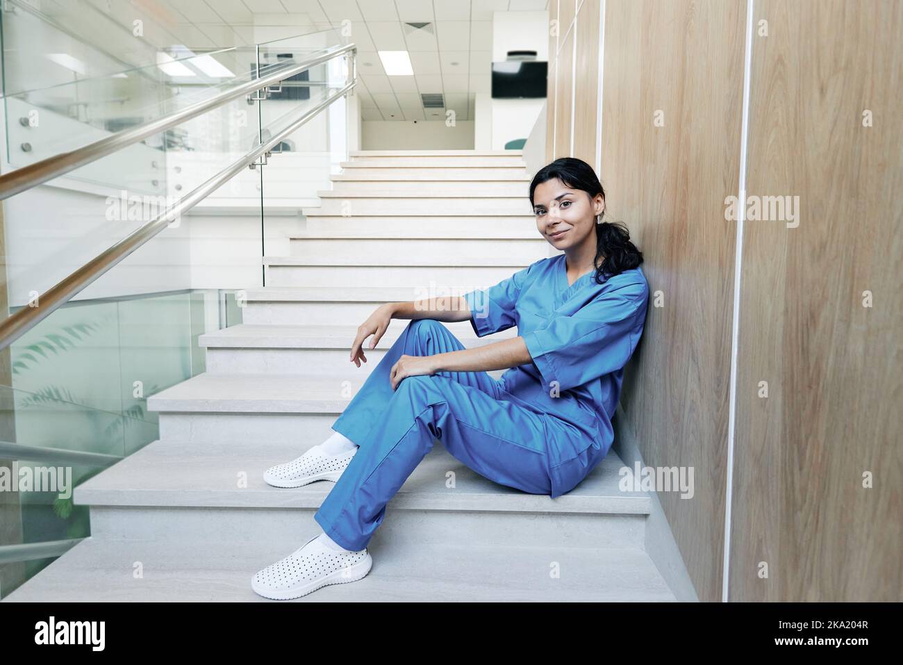 Portrait of Asian nurse who sitting on stair in hospital while break ...