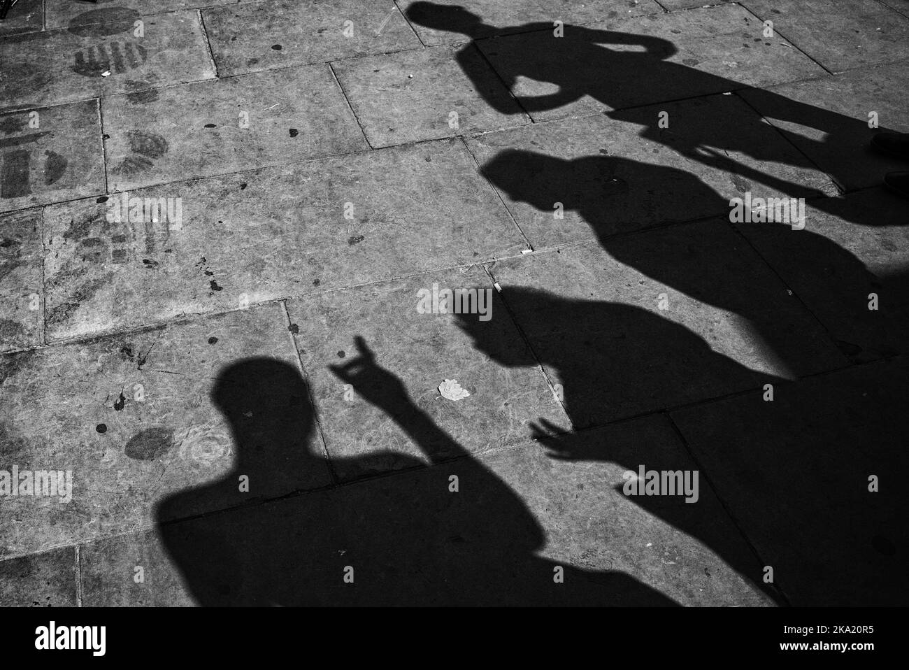 A man points at others during an argument, seen in shadow on the street ...