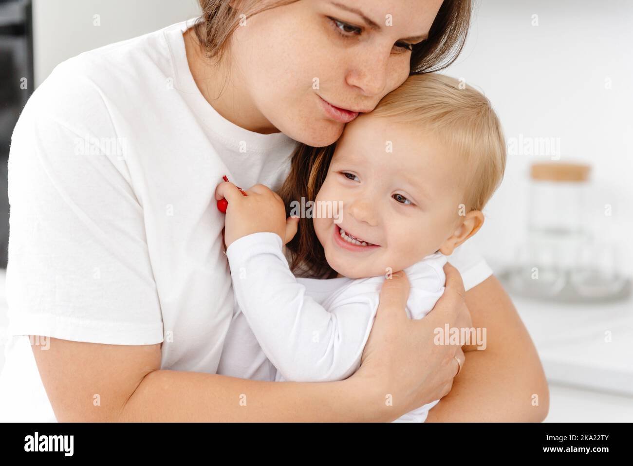 A loving mother cuddling her baby at home. A vivid portrait of a happy mother, with her son. A ...