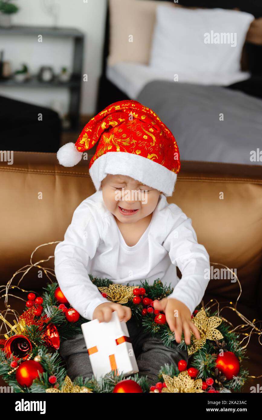 Christmas child opens a gift, happy boy tries to open a box of gifts ...