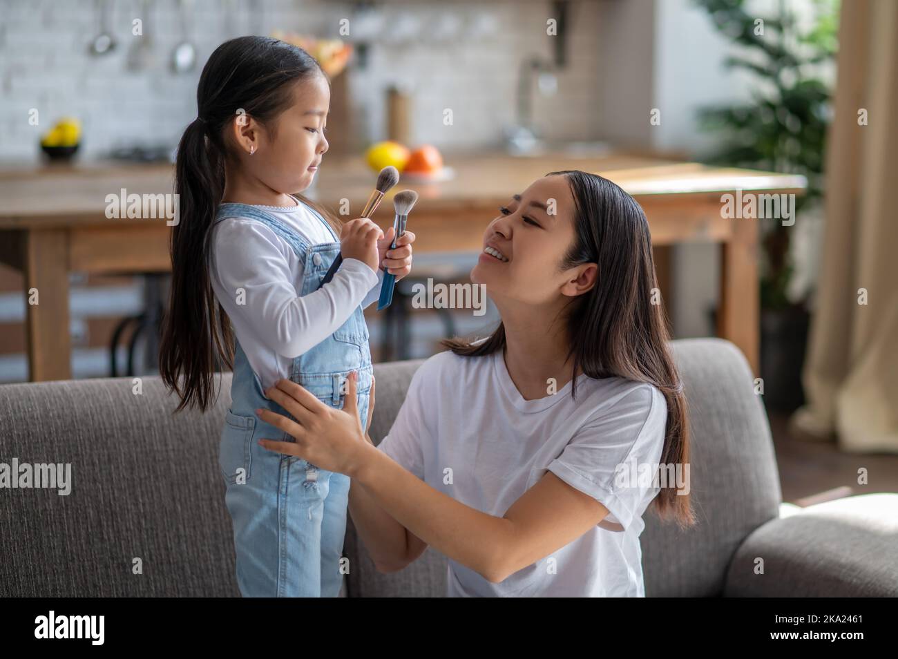 Child preparing to apply makeup to her female parent face Stock Photo ...