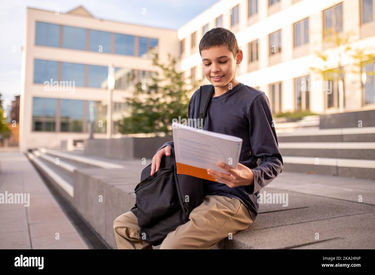 Smiling teen reading a title on the book cover Stock Photo - Alamy