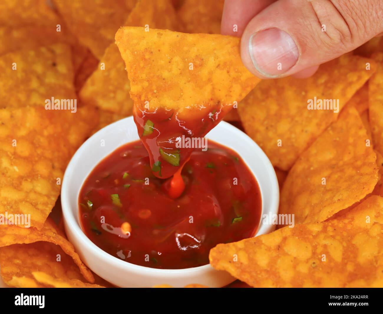 close up of dipping a tortilla chip in hot spicy salsa with chili ...