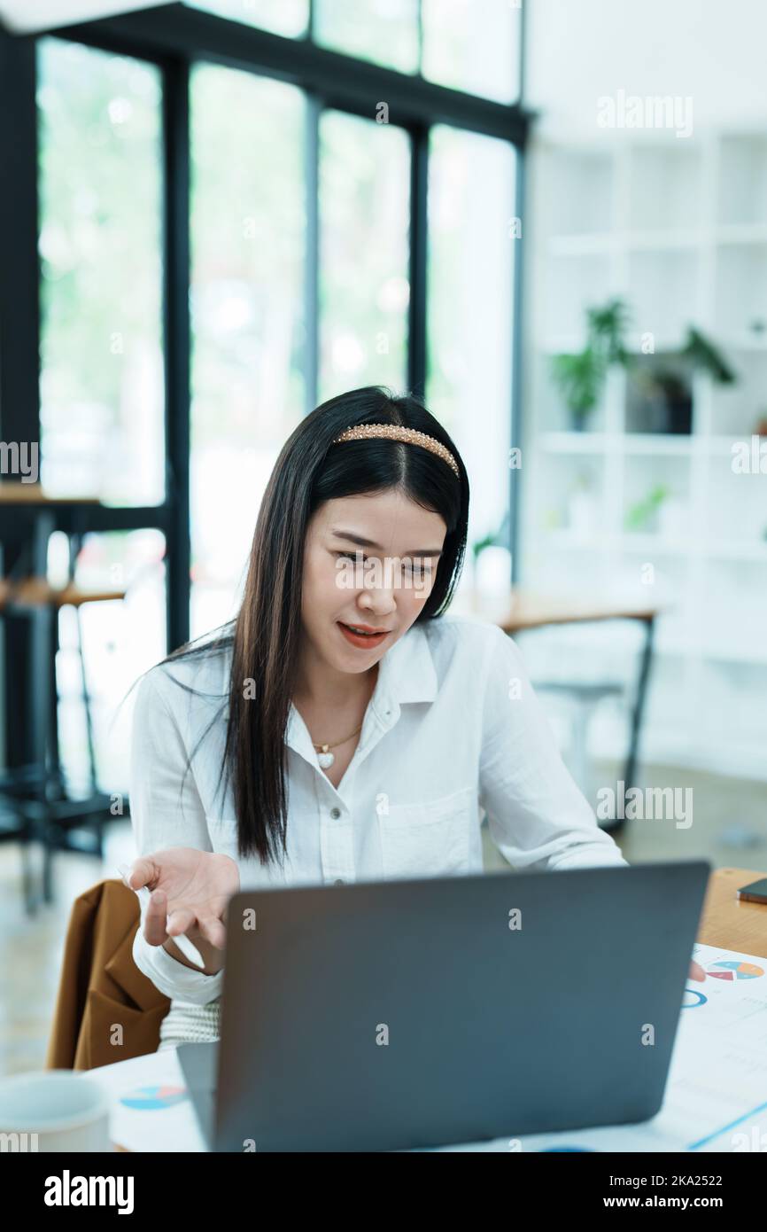 Portrait of a beautiful Asian teenage girl using computer for video ...