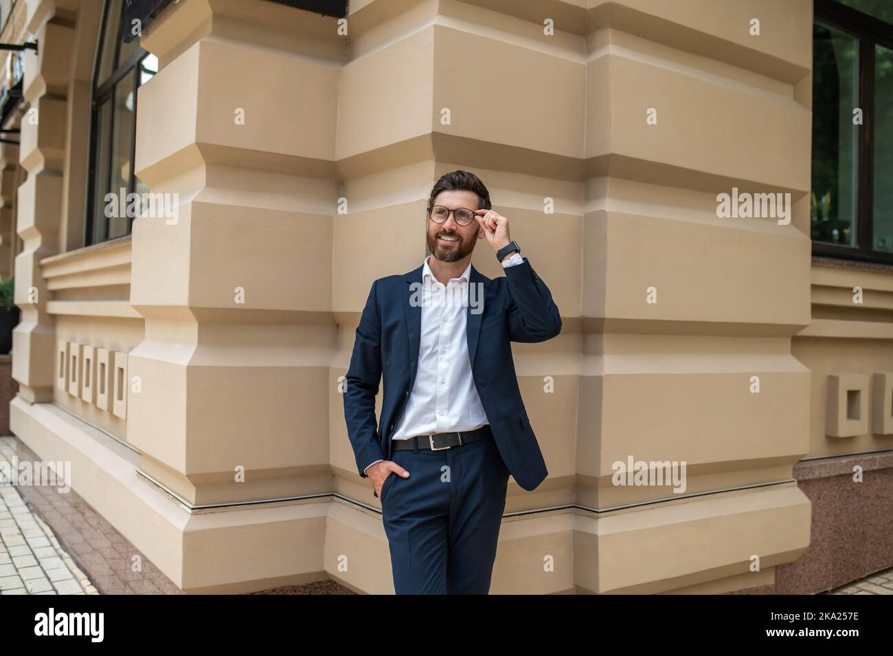 Elegant man standing near the wall of a big building Stock Photo - Alamy