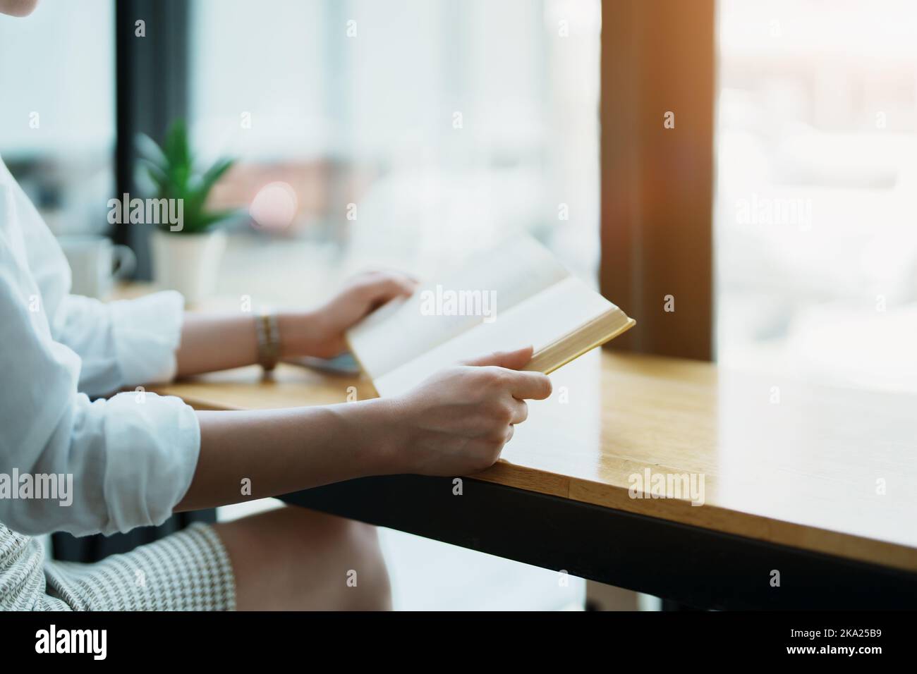 Portrait of a beautiful Asian female employee reading a book during her ...