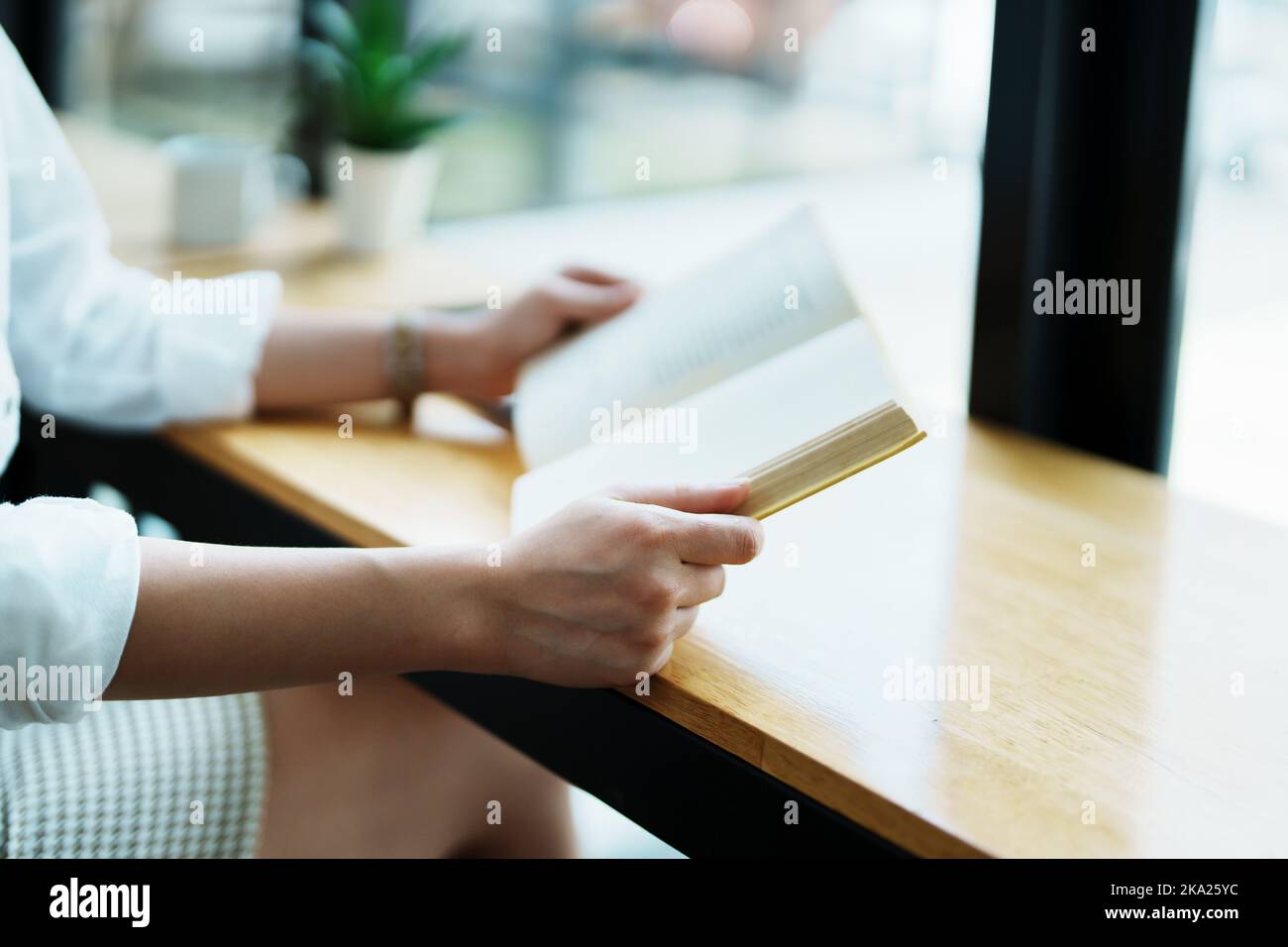 Portrait of a beautiful Asian female employee reading a book during her ...