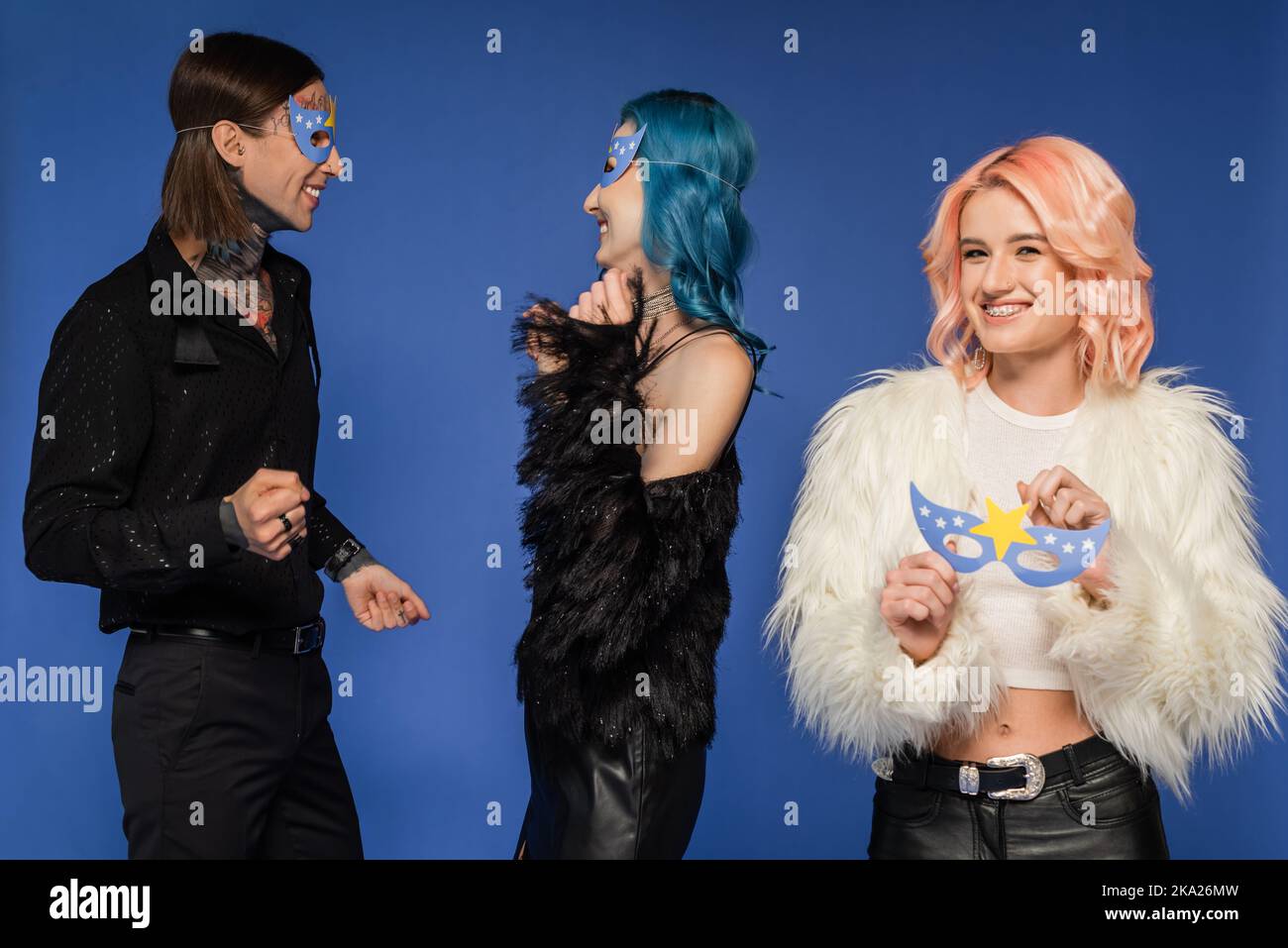 queer person holding party mask and looking at camera near nonbinary ...