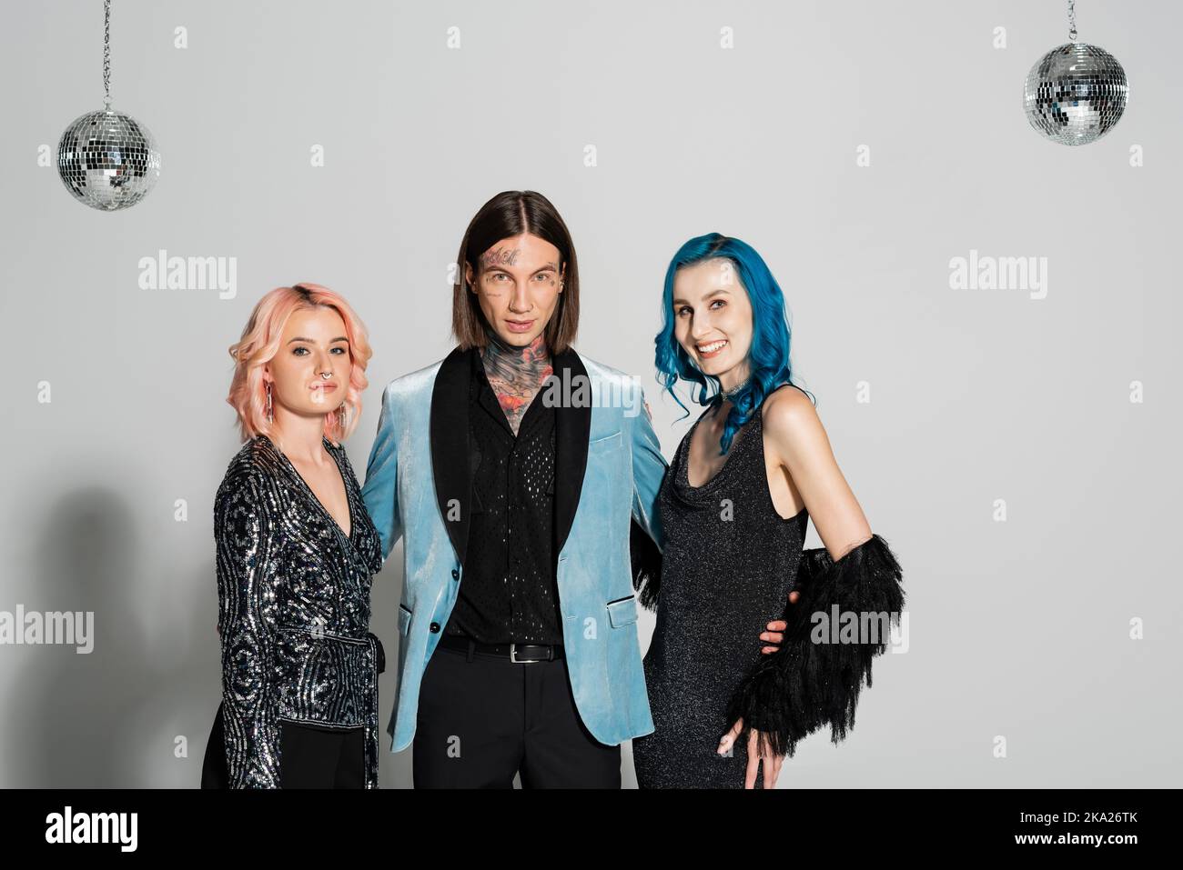 tattooed queer person looking at camera near elegant nonbinary friends ...