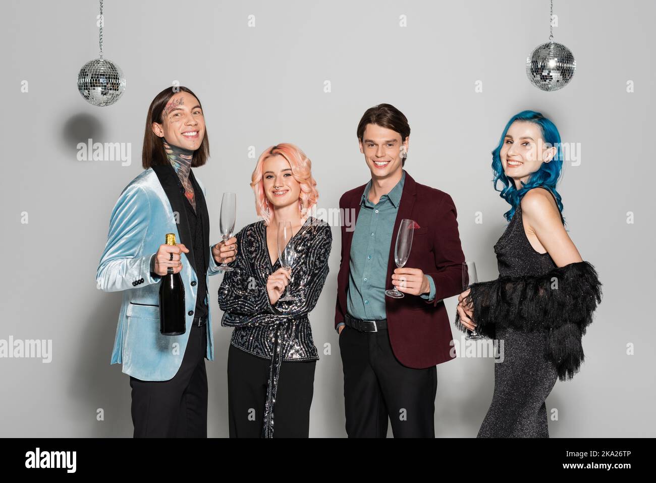 elegant nonbinary friends with champagne smiling at camera near disco ...