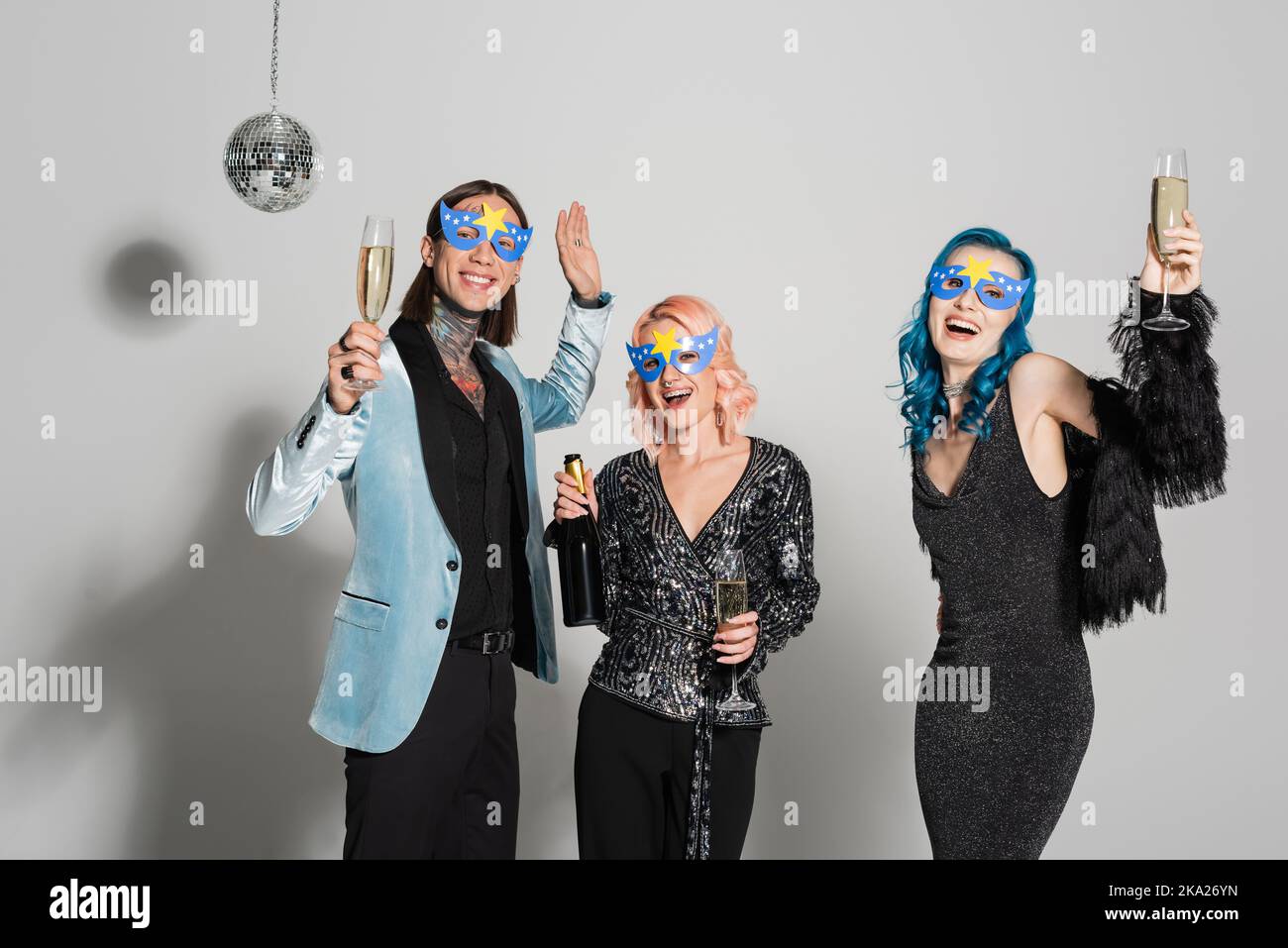 tattooed nonbinary person holding champagne glass and waving hand near ...