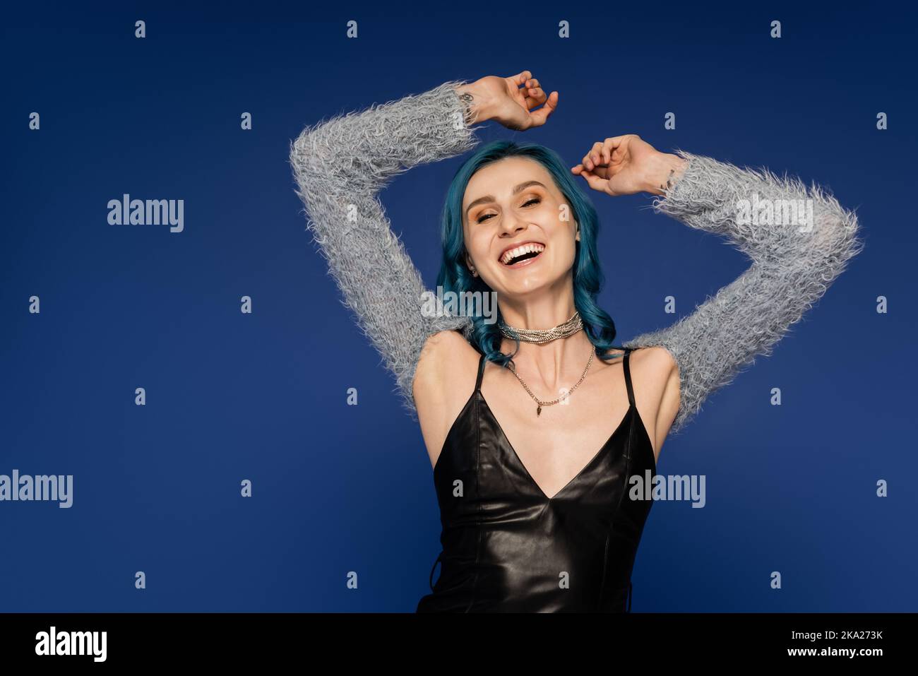 cheerful woman in black leather dress and fluffy sleeves dancing with ...