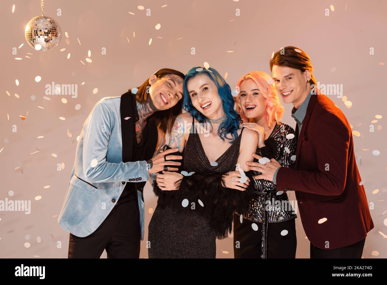happy and stylish queer friends embracing and looking at camera under ...