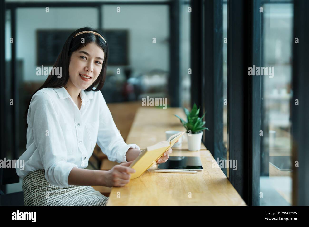Portrait of a beautiful Asian female employee reading a book during her ...