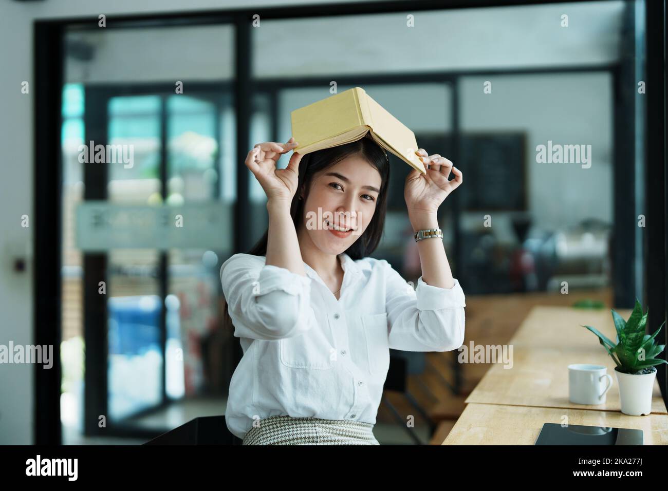 Portrait of a beautiful Asian female employee reading a book during her ...