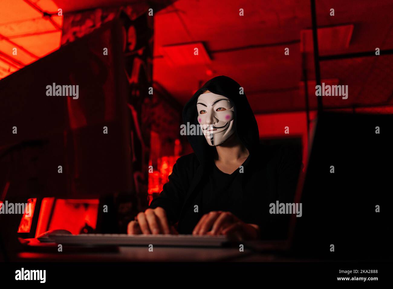 Unrecognizable Hacker Man Wearing Anonymous Mask And Sweatshirt Typing