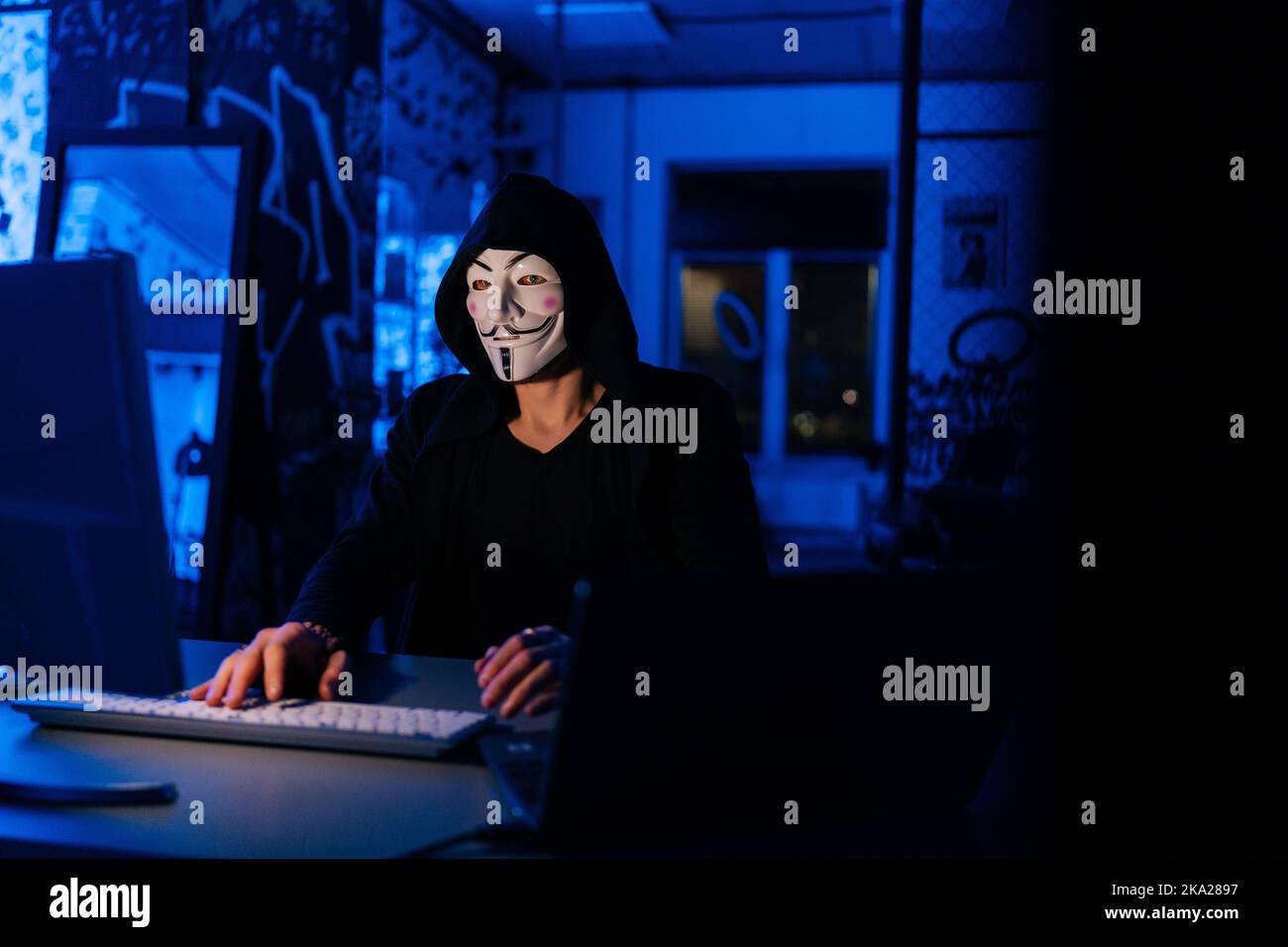 Portrait Of Unrecognizable Dangerous Hacker Man In Anonymous Mask Starting Breaking Computer