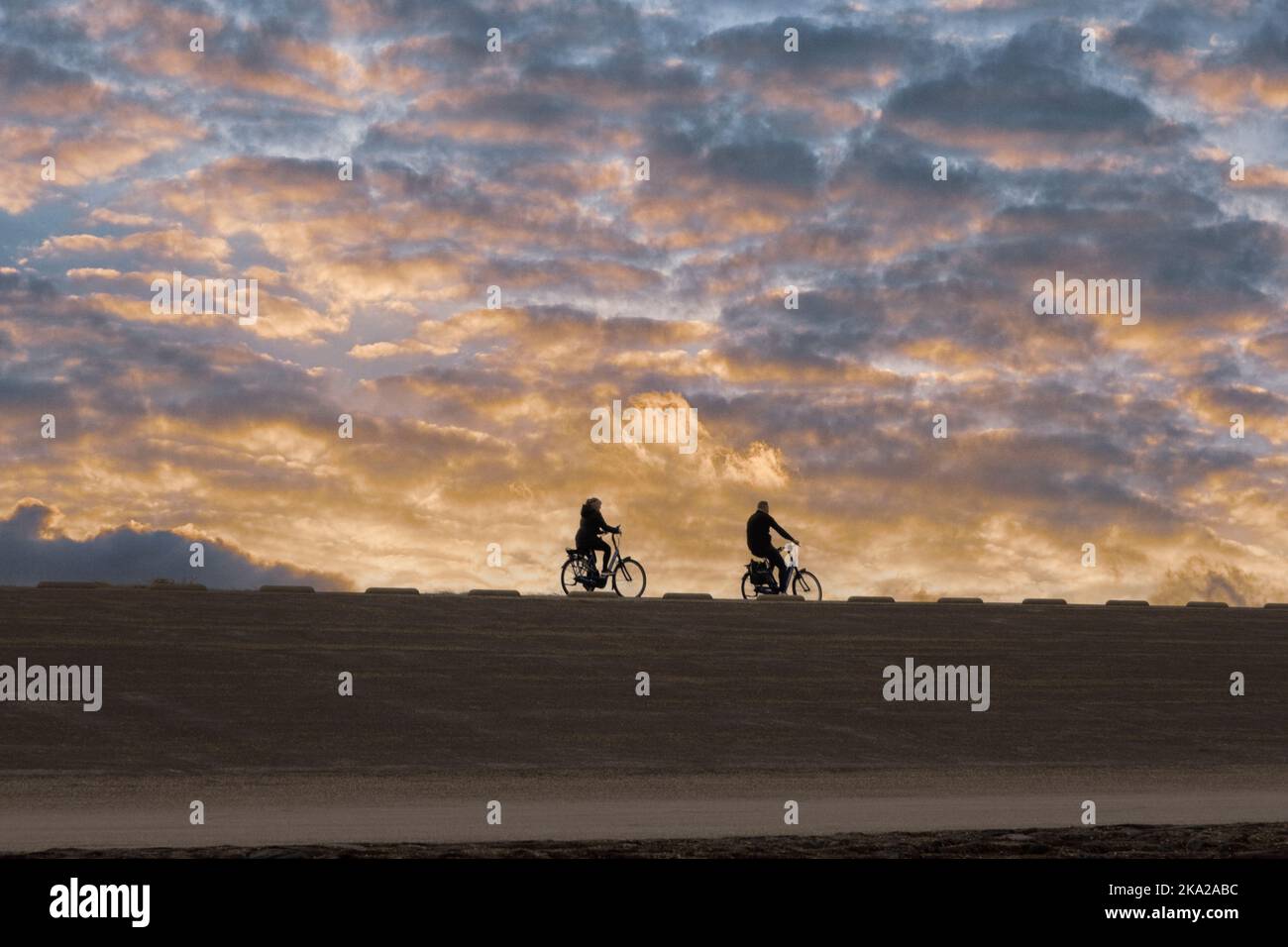 People on bikes on a Dutch dike at sunset Stock Photo - Alamy