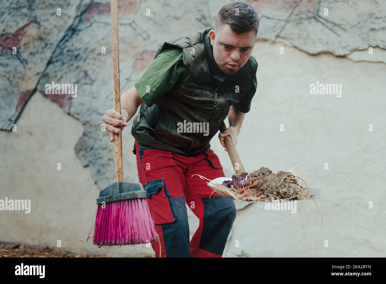 Caretaker with down syndrome in zoo cleaning animal enclosure. Concept ...