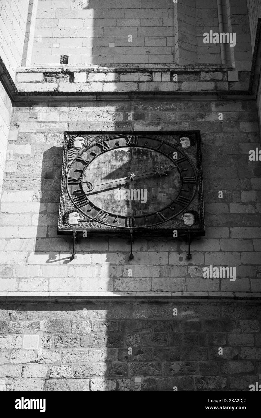 The vertical grayscale view of an old clock on a medieval building's ...