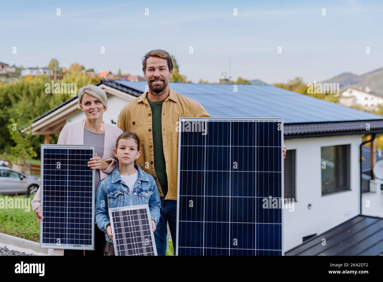 Happy family near their house with solar panel. Alternative energy ...