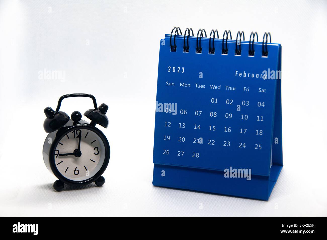 Alarm clock pointing at 9 o'clock with February 2023 calendar on white ...