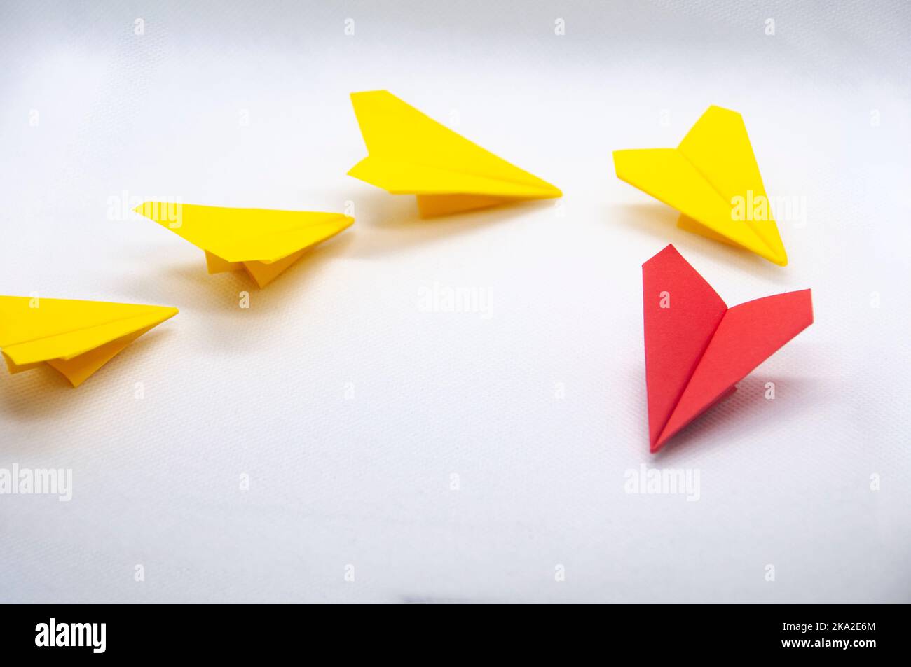 Red paper plane origami leading yellow planes on white background ...